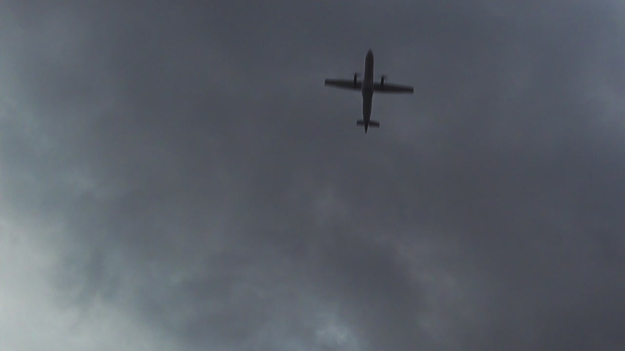Plane flying overhead in a dark cloudy sky Premium Stock Video Footage