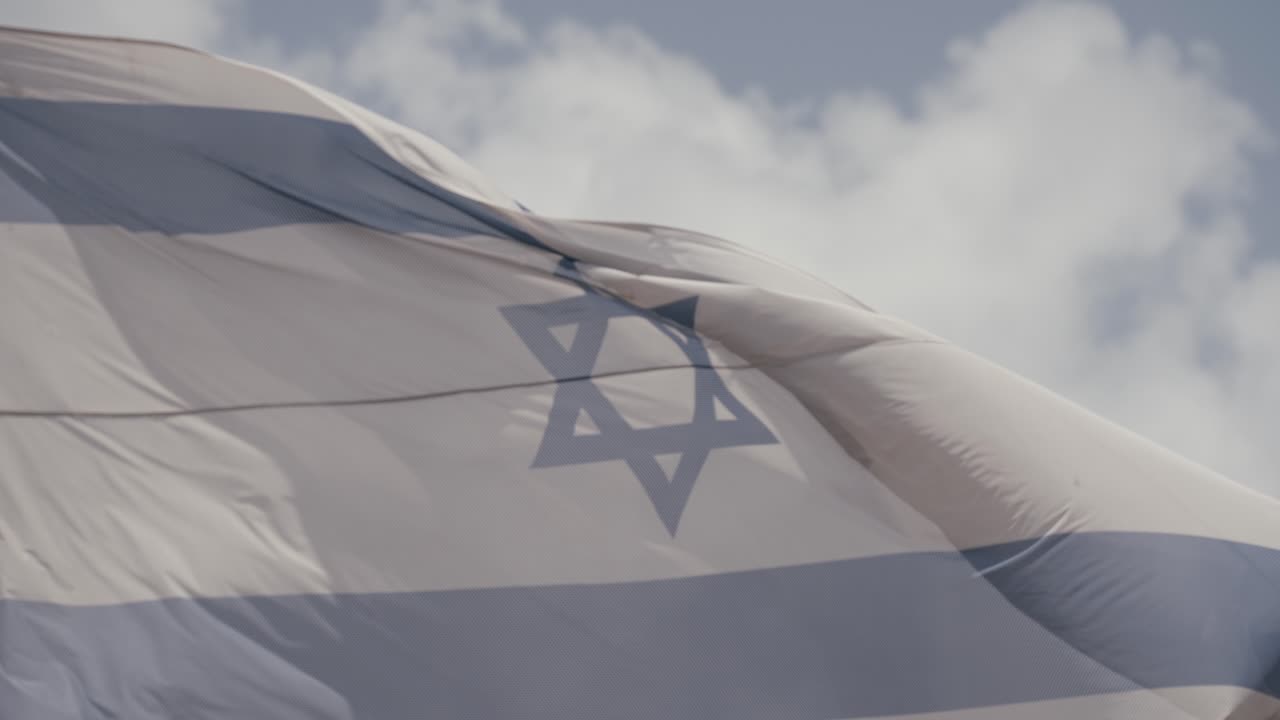 Premium stock video - Slow-motion: israeli flag waves against a blue ...