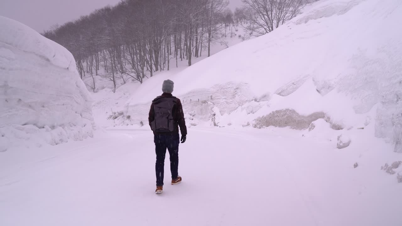 Male Tourist Walking Through Snowed In Landscape With High Snow Walls ...
