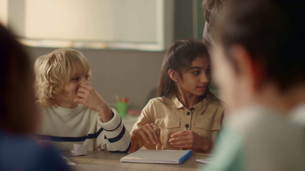 Teacher talking with students at round table in classroom. Pupils ...