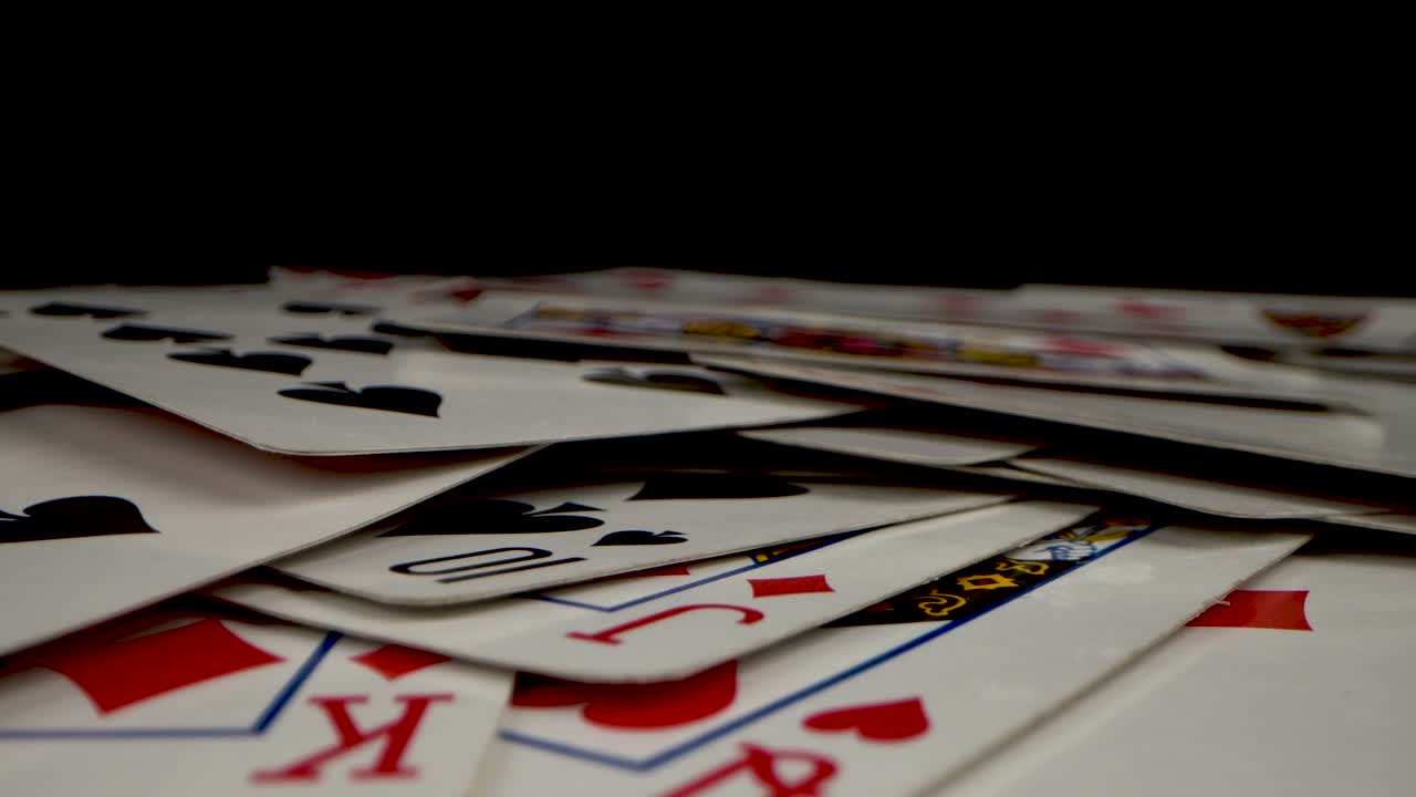 Premium stock video - Scattered playing cards in dark ambiance