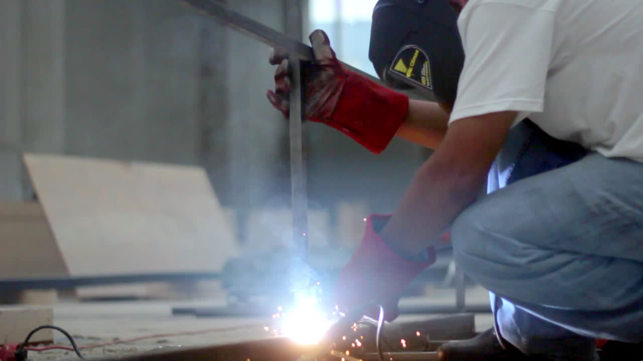 Focused welder fuses steel beams, surrounded by flying sparks and smoke ...