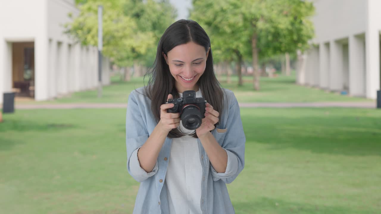 Premium stock video - Happy indian girl clicking photos using a camera