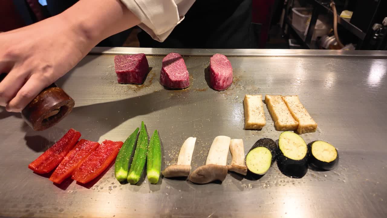 Chef prepares kobe steak and vegetables on a hot grill at osaka's ...