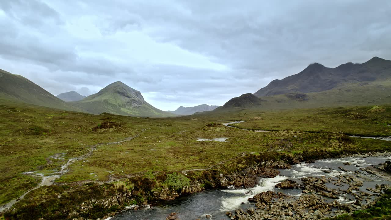 Premium stock video - Epic scottish mountain range shot pulls back and reveals rocky river, skye