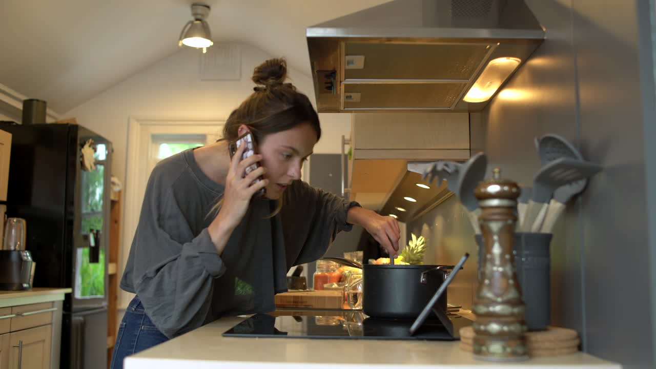 Free stock video - Low angle shot of young woman on phone whilst cooking