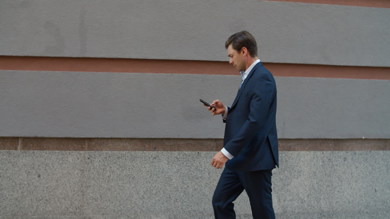 Side view business man walking with phone. man using phone near modern ...
