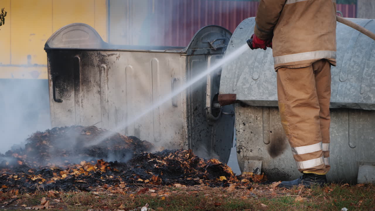 Premium stock video - Firefighter puts out a fire near garbage bins ...