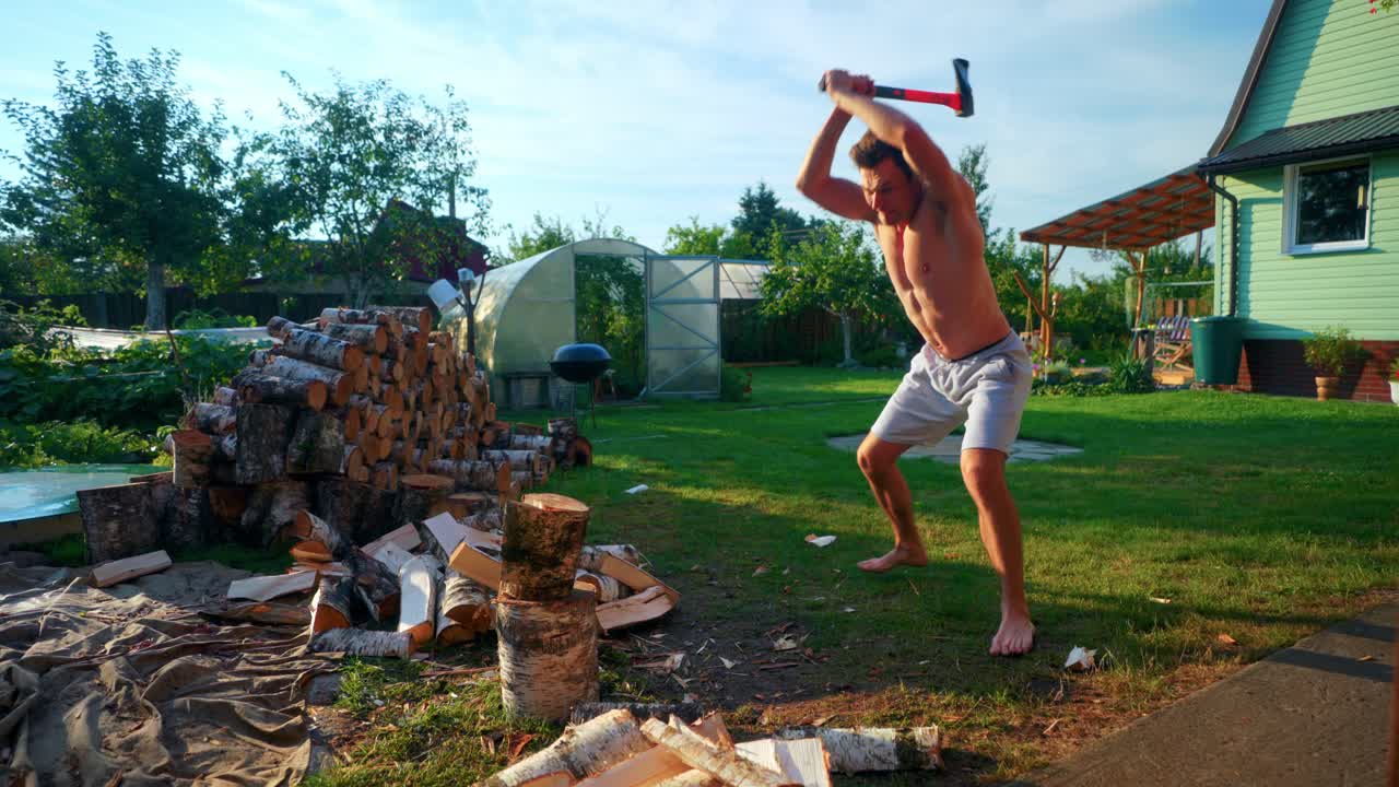 Premium stock video - Young man with muscular body chopping wood with ...