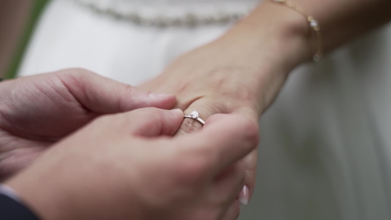Fiancé gently caresses his bride-to-be’s hand, showcasing the ...