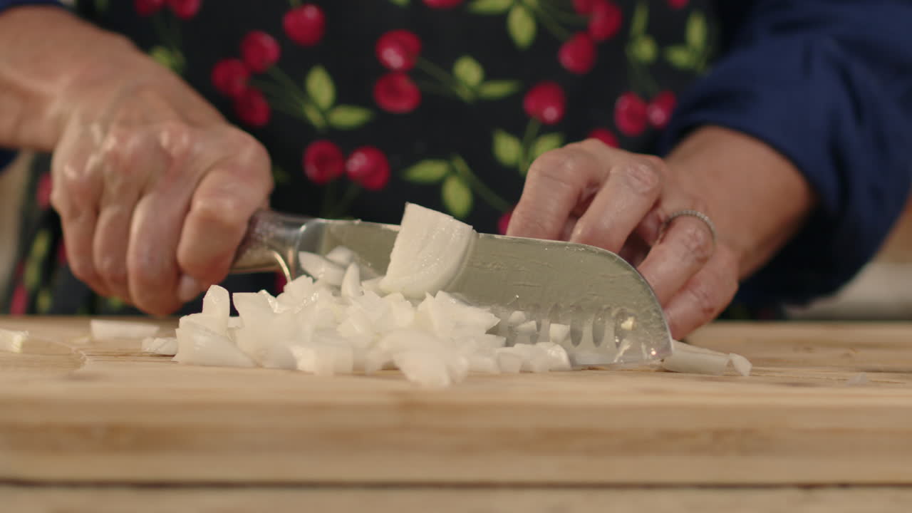 Woman chopping and mincing onion with a knife on cutting board in slow ...