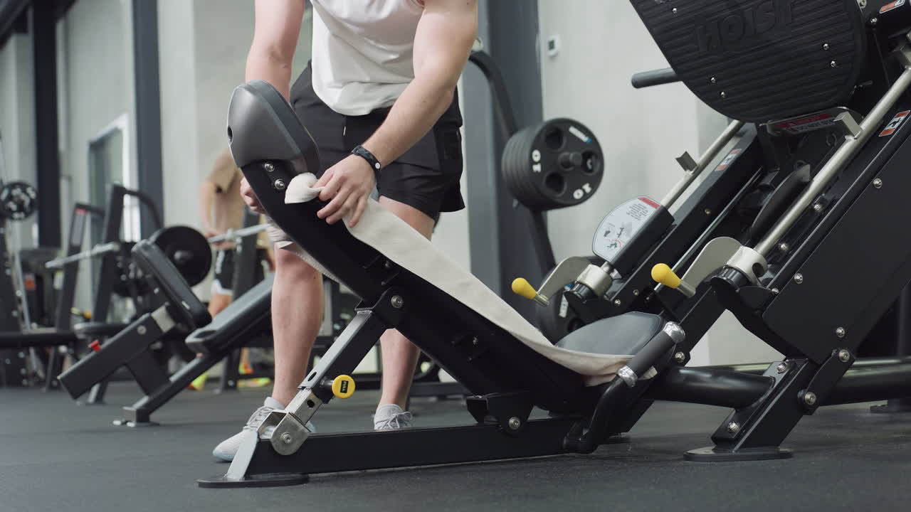 Muscular man adjusts seat on leg press machine seats comfortably ...