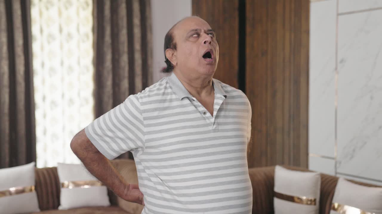 Premium stock video - Fat indian old man suffering from back pain