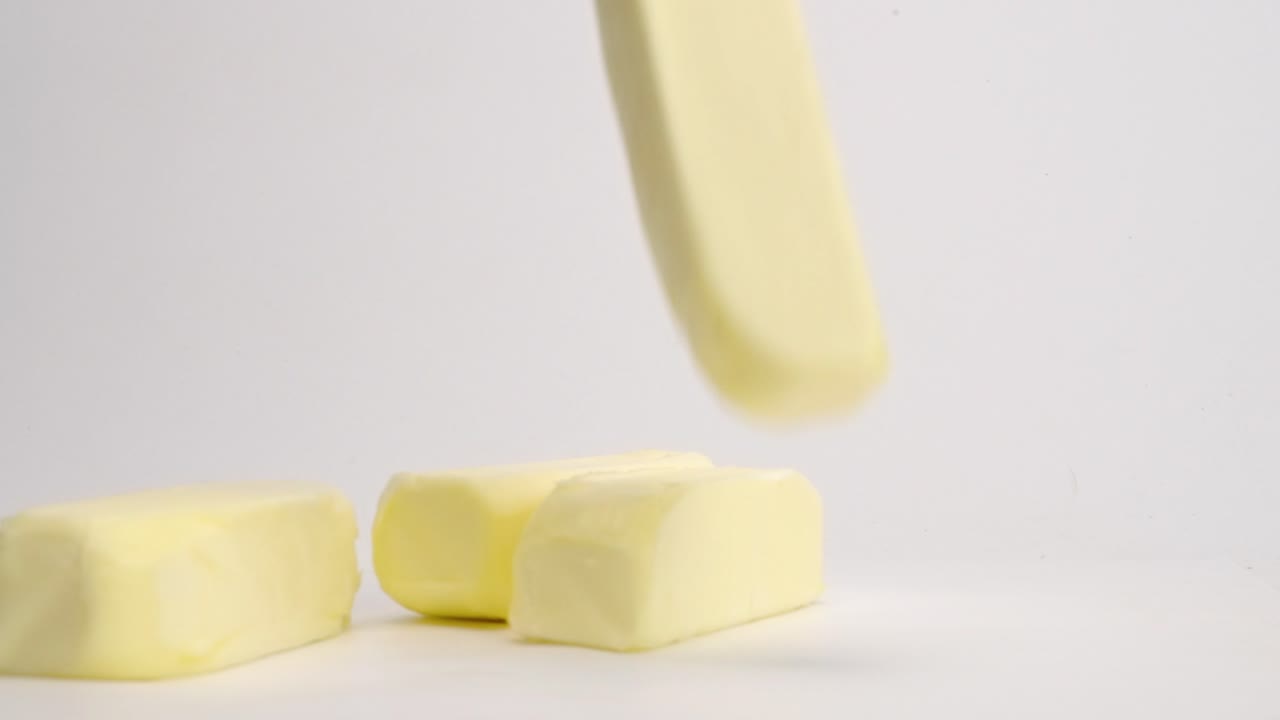Whole, unwrapped sticks of yellow butter cubes falling and bouncing ...