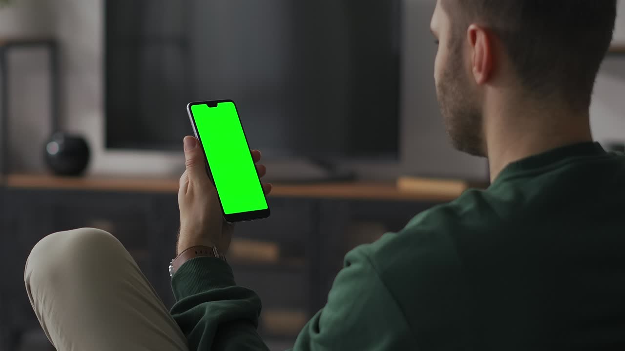 Young man is holding mobile vertically and looking on display, swiping ...