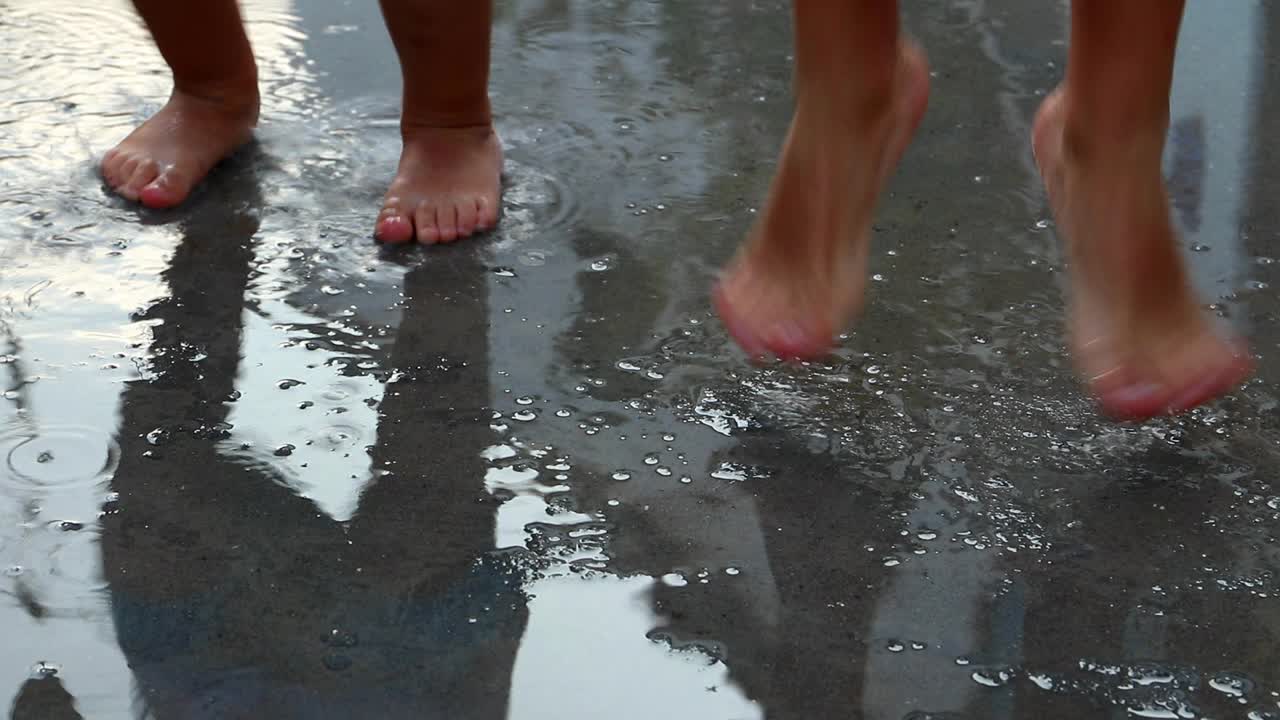 Siblings Children happy wet feet jumping in slow motion on water puddle ...