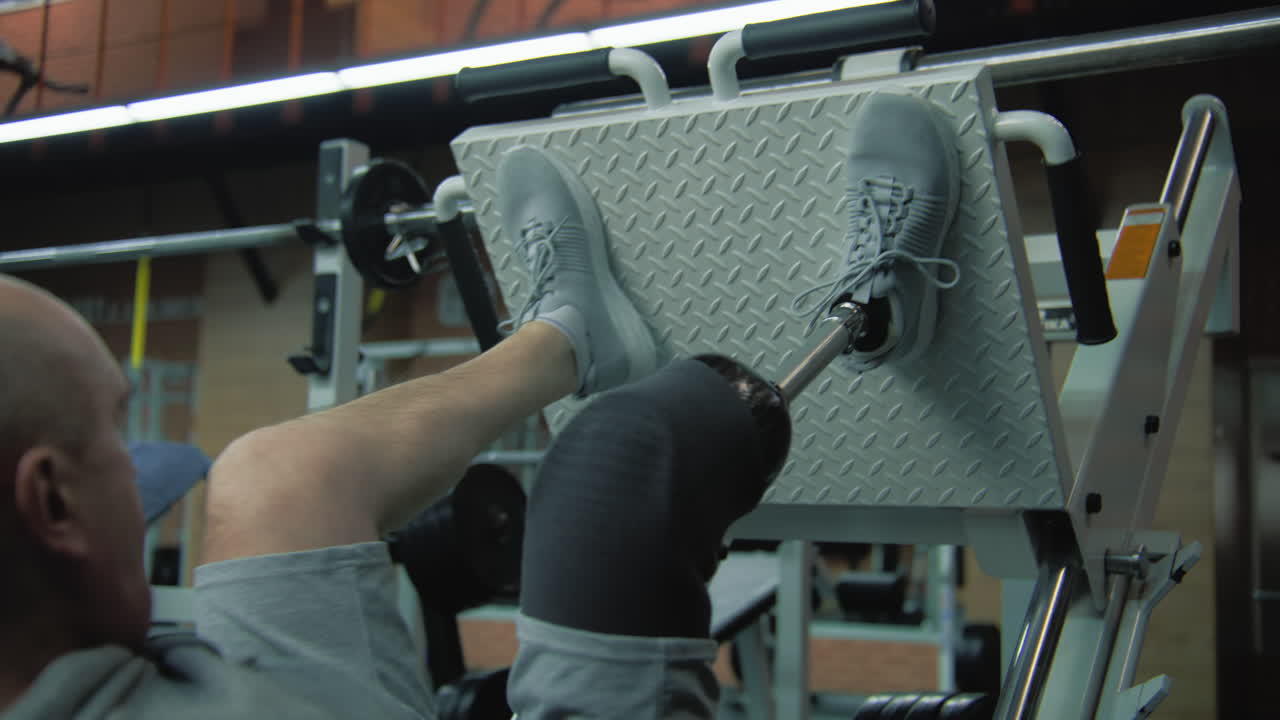 Motivated sportsman with prosthetic leg trains on leg press machine in ...