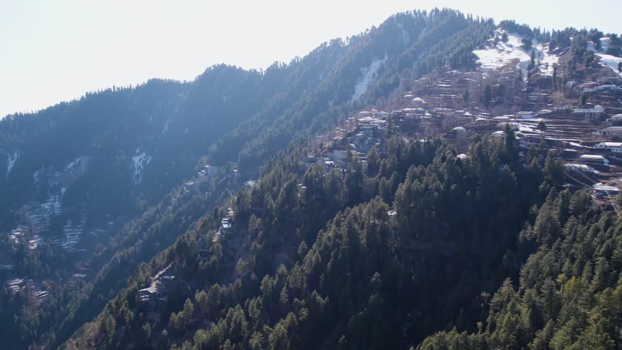Snow-capped hill station surrounded by a dense forest in Ayubia ...