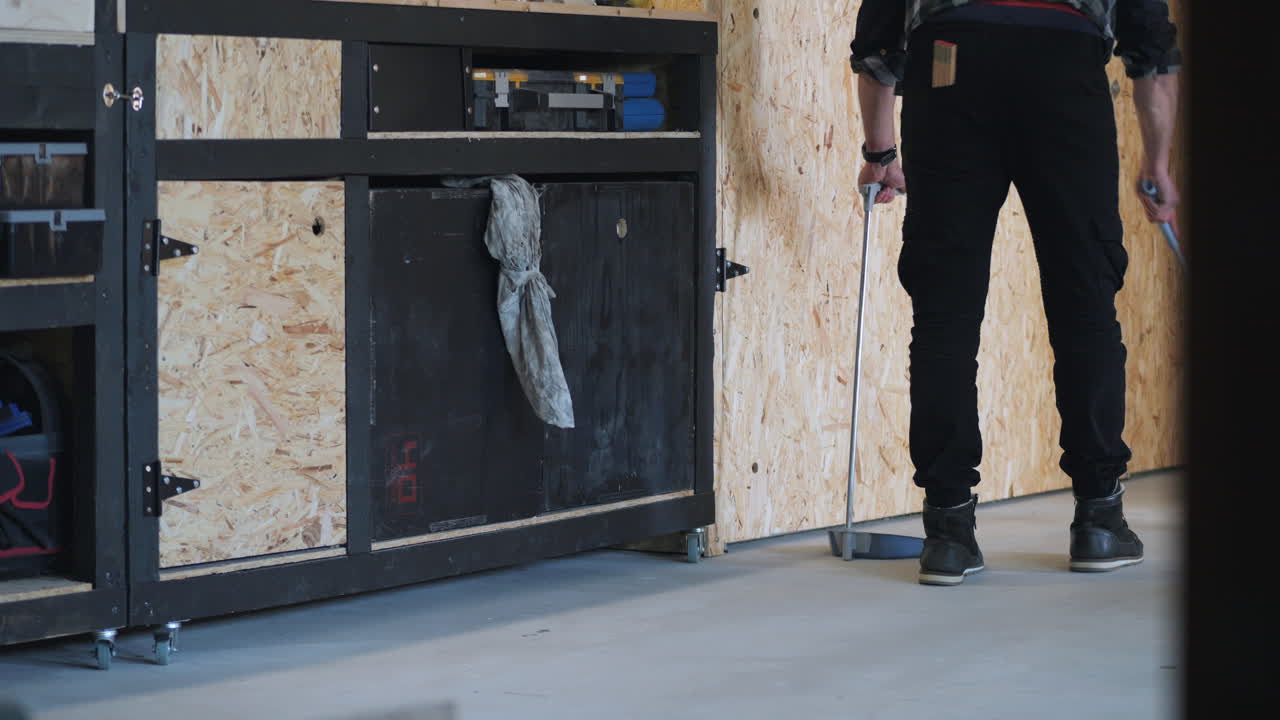 Medium shot of Young Man Sweeping workshop, sideways dolly | Premium ...
