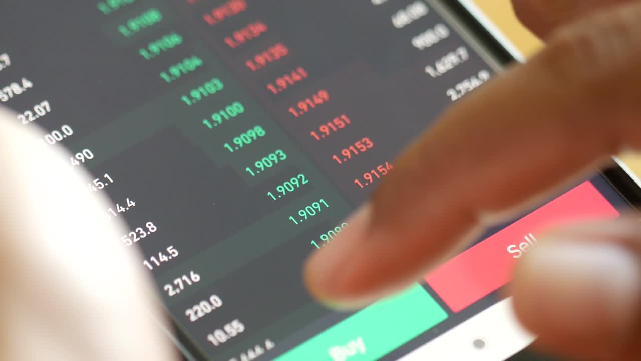 Premium stock video - Hands with a mobile phone, checking stock market data