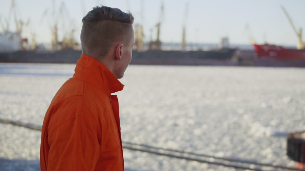 Harbor worker in orange uniform is walking by the sea. slow motion ...