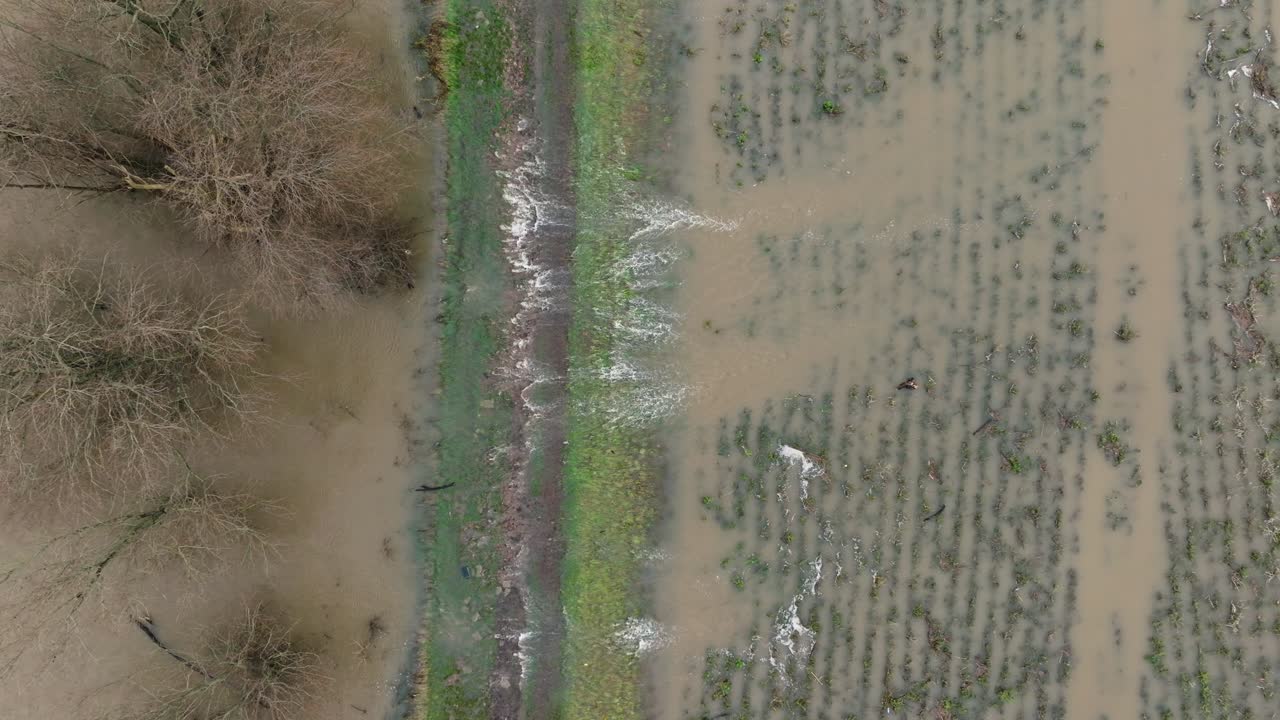 Medium aerial birdseye view of flood waters overrunning a levy and ...