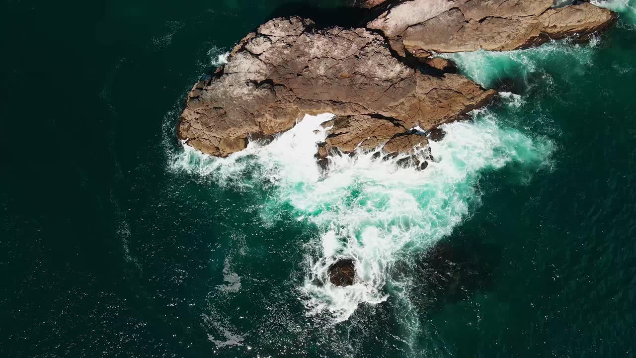 Premium stock video - Watching the tide push waves against rocks from above