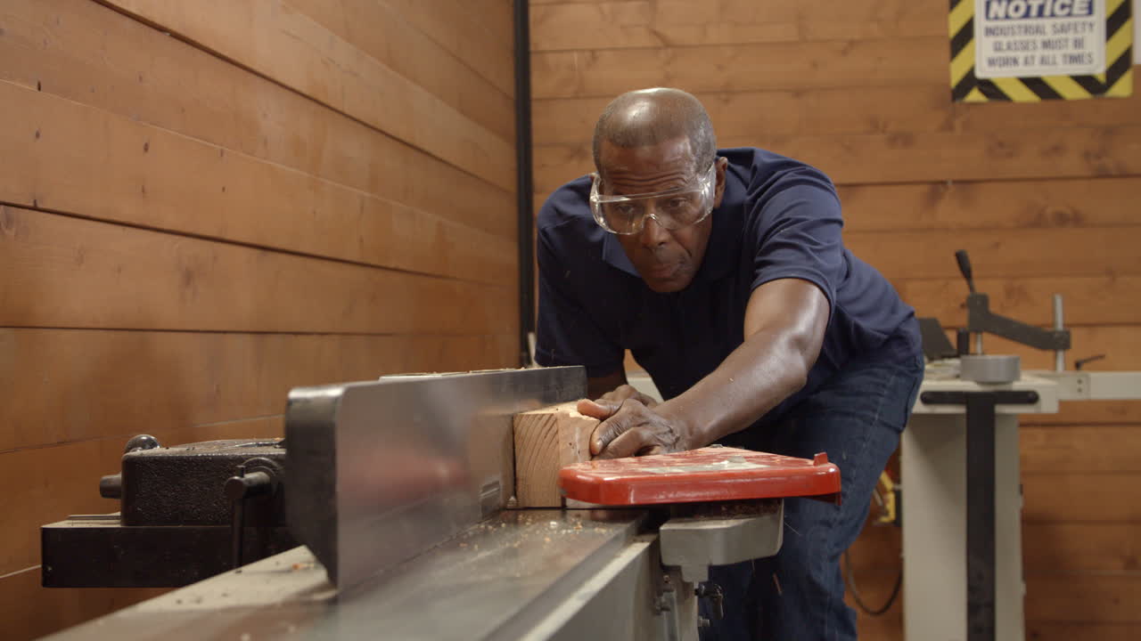 Premium stock video - Male carpenter using plane in woodworking woodshop