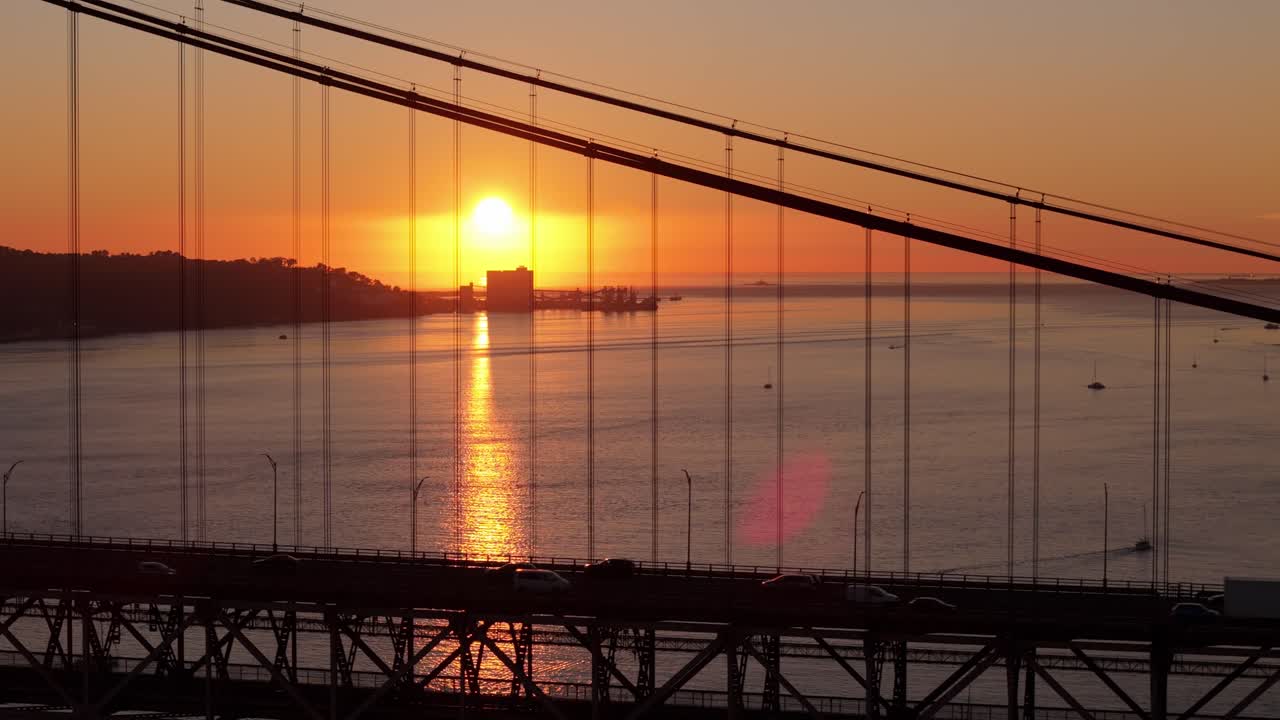 Sunset ray of light cuts between suspension bridge rail beam supports ...