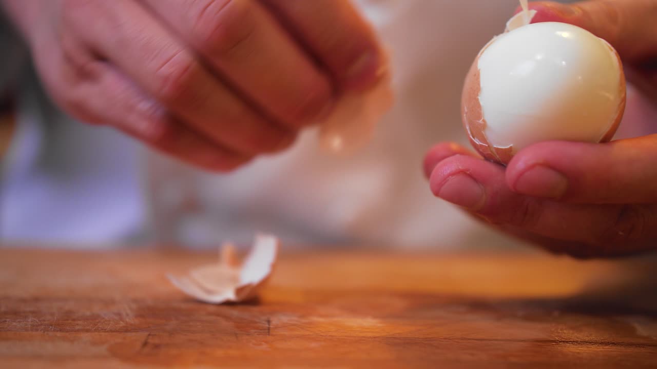 Cook peels an egg on a wooden board Premium Stock Video Footage