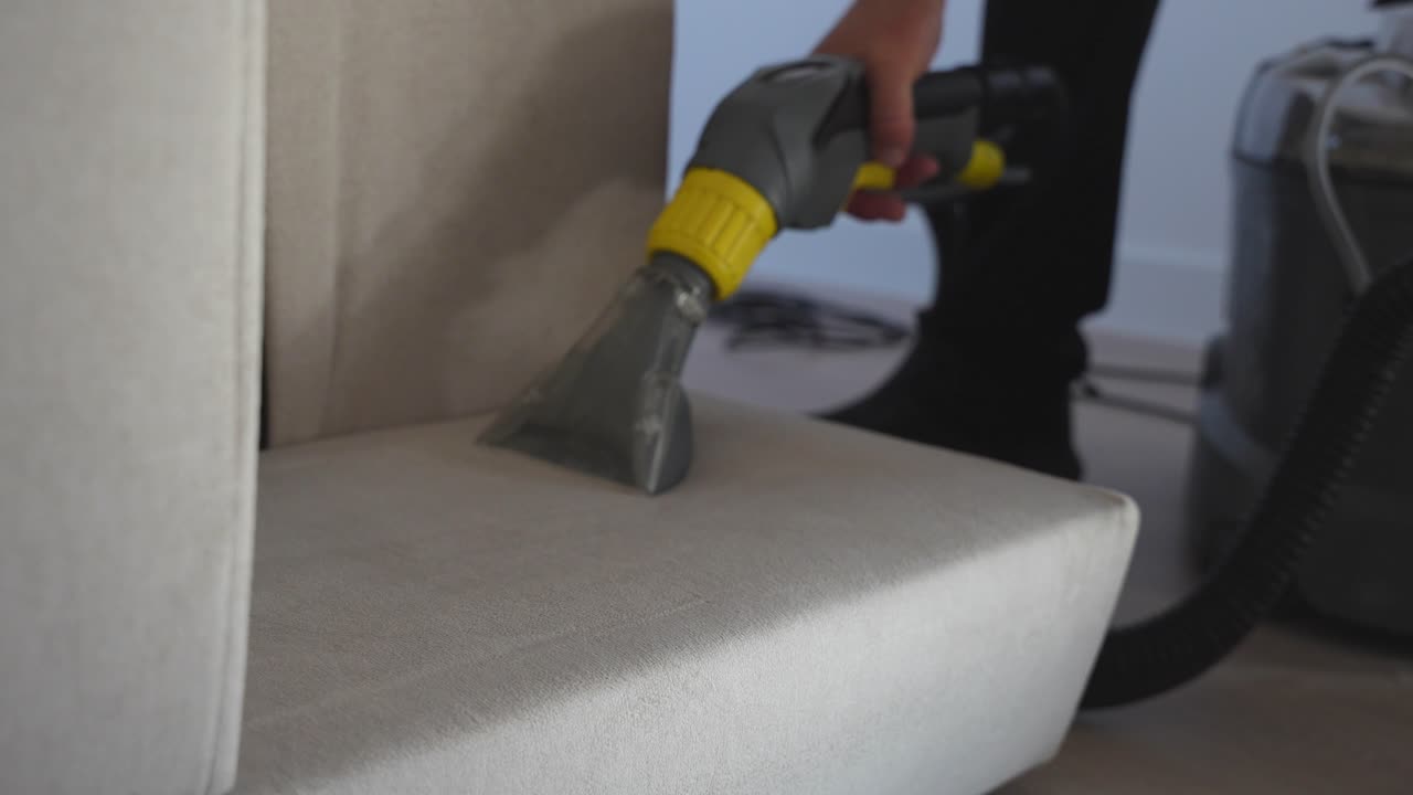 Close up of pressure washer cleaning sofa cushion with ionized water ...
