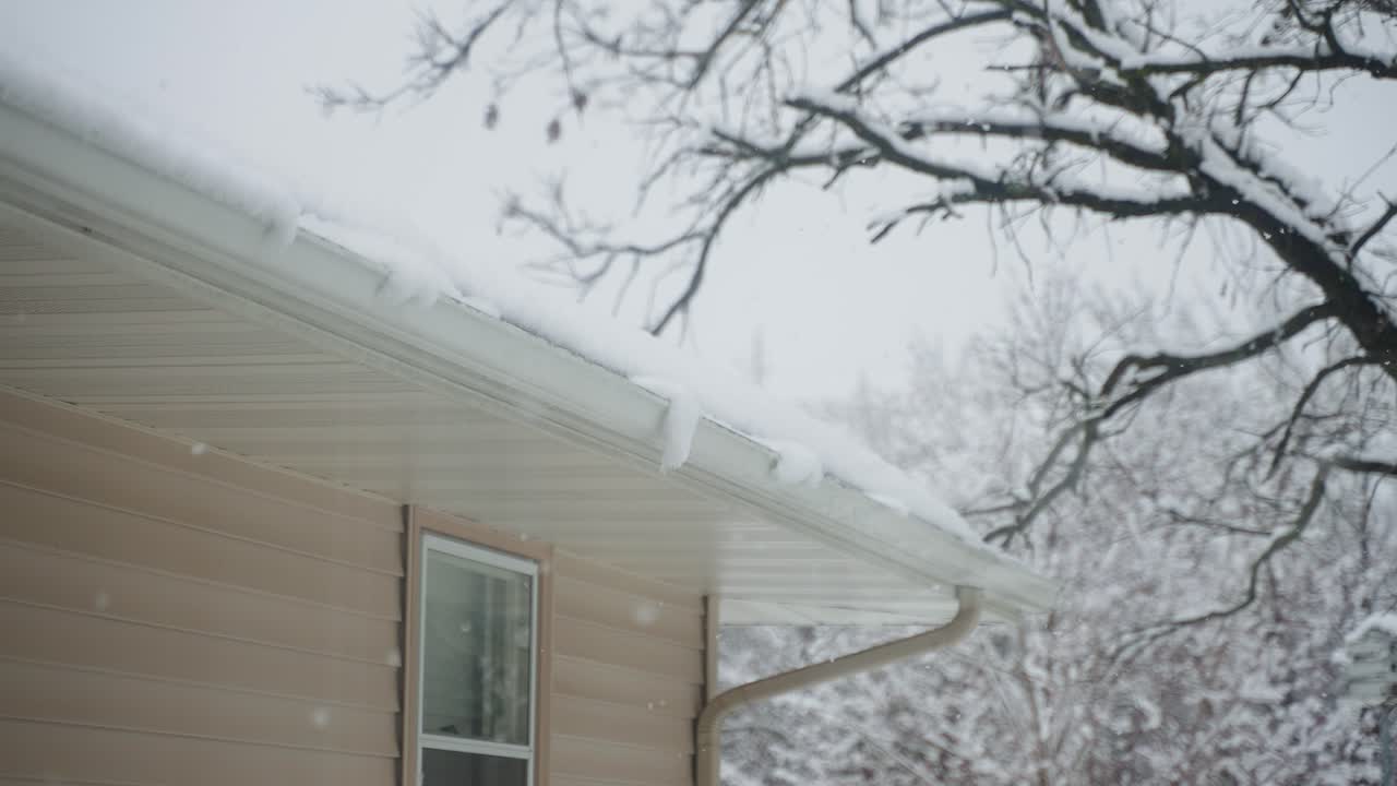 An ice dam building up on a roof near the gutters during snowstorm ...