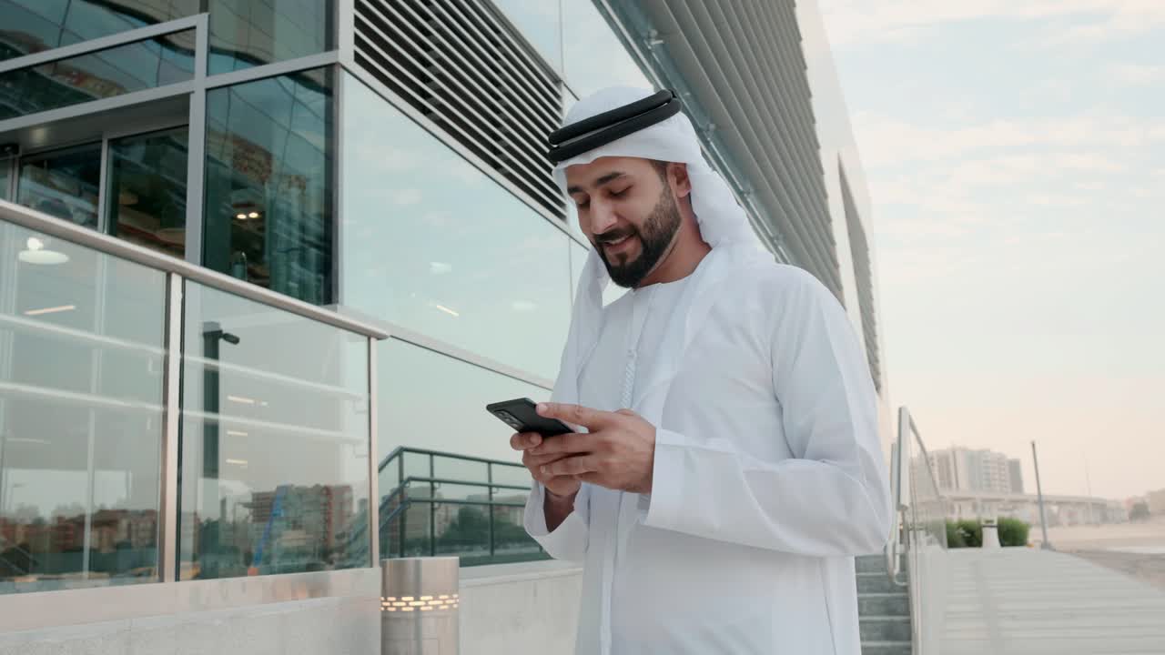 Happy Arab man in Kandoora using cell phone device Arabic Emirati local ...