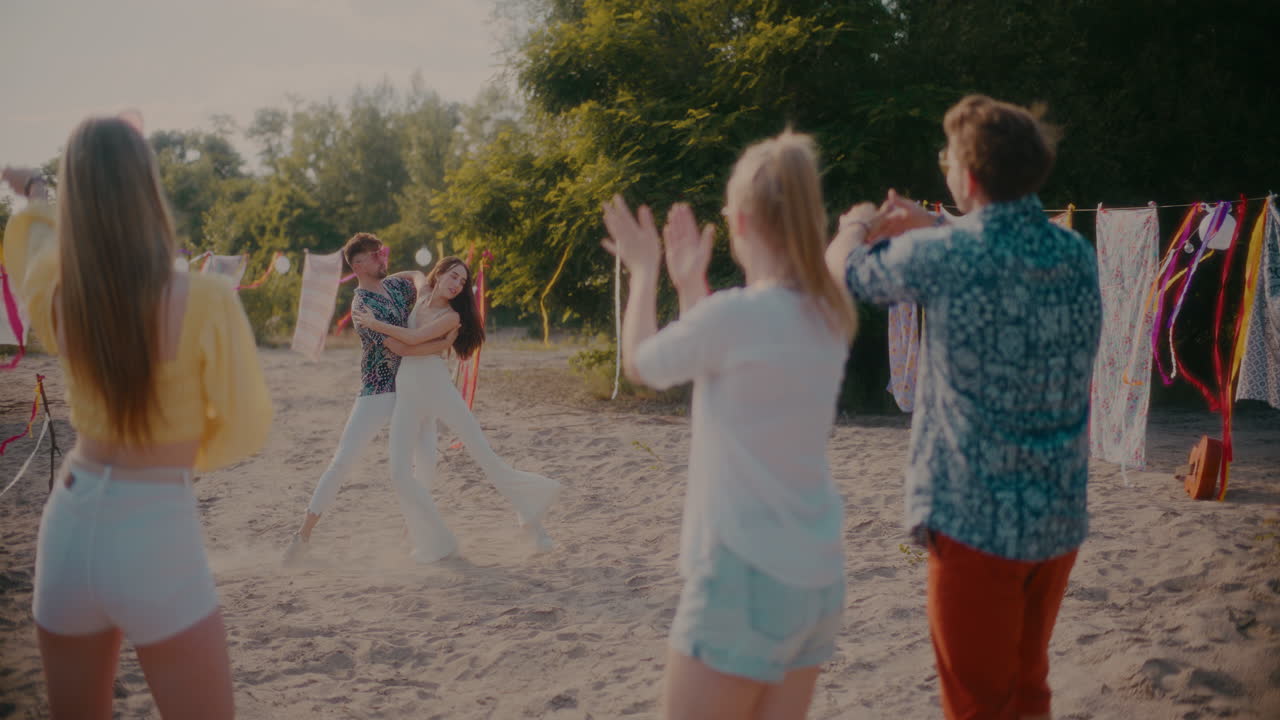 Young friends clapping and cheerful couple dancing bachata at beach ...