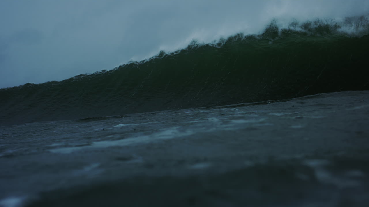 Lip of ocean wave crashes on stormy water surface as rain drops fall on ...