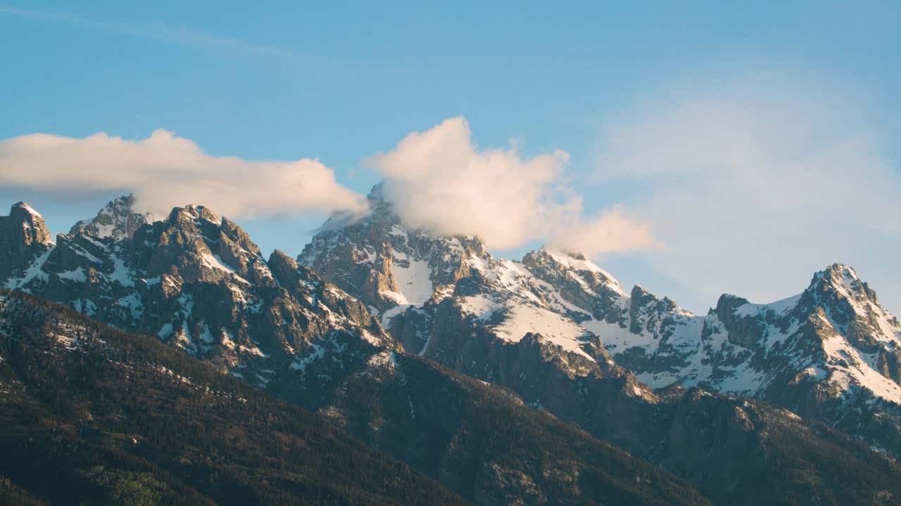 Timelapse of snow covered mountains at sunrise with clouds blowing by ...