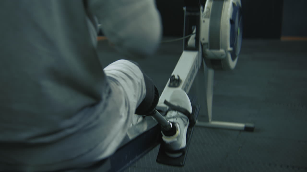 Athletic Man With Prosthetic Leg Exercises On Rowing Machine In Modern ...