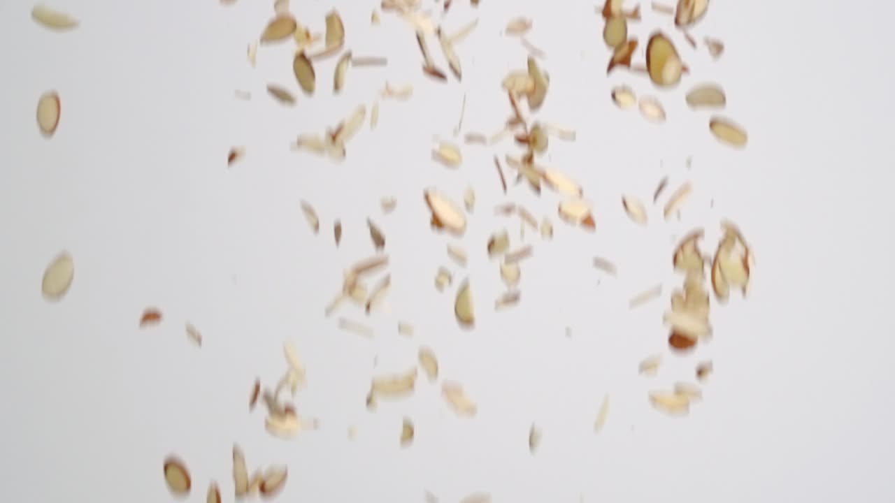 Premium stock video - Sliced almond nut pieces raining down on white ...