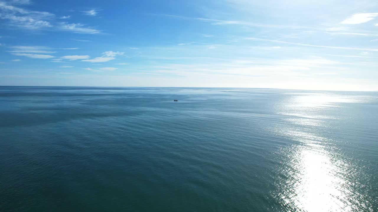 Wide open sea with one boat, drone aerial view of blue bright sky, sun ...