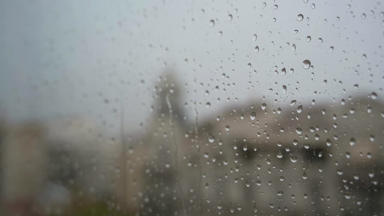 A slow-motion of raindrops seen through a window during heavy rainfall ...