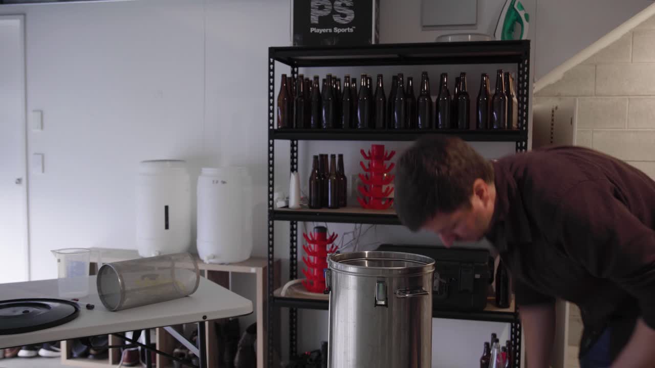 A man setting up brew kettle equipment in garage home craft beer ...