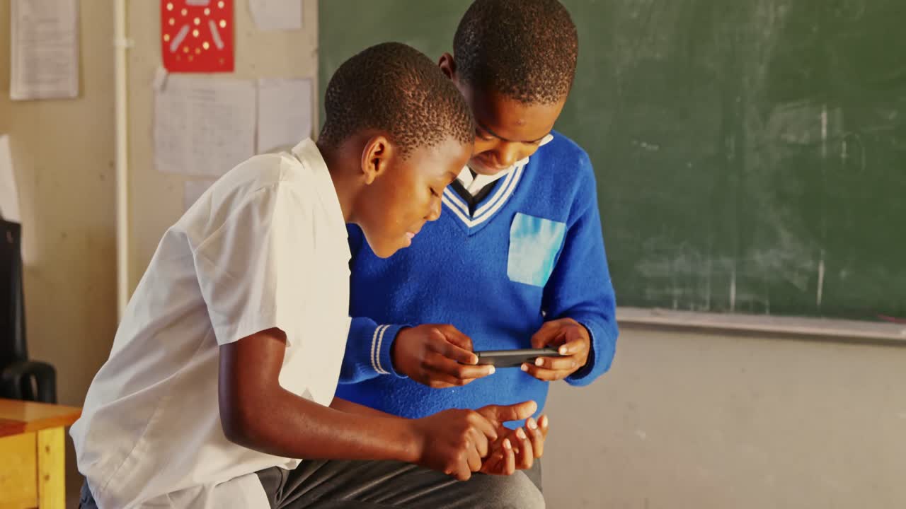 Schoolboys using a smartphone during a break at a township school 4k ...