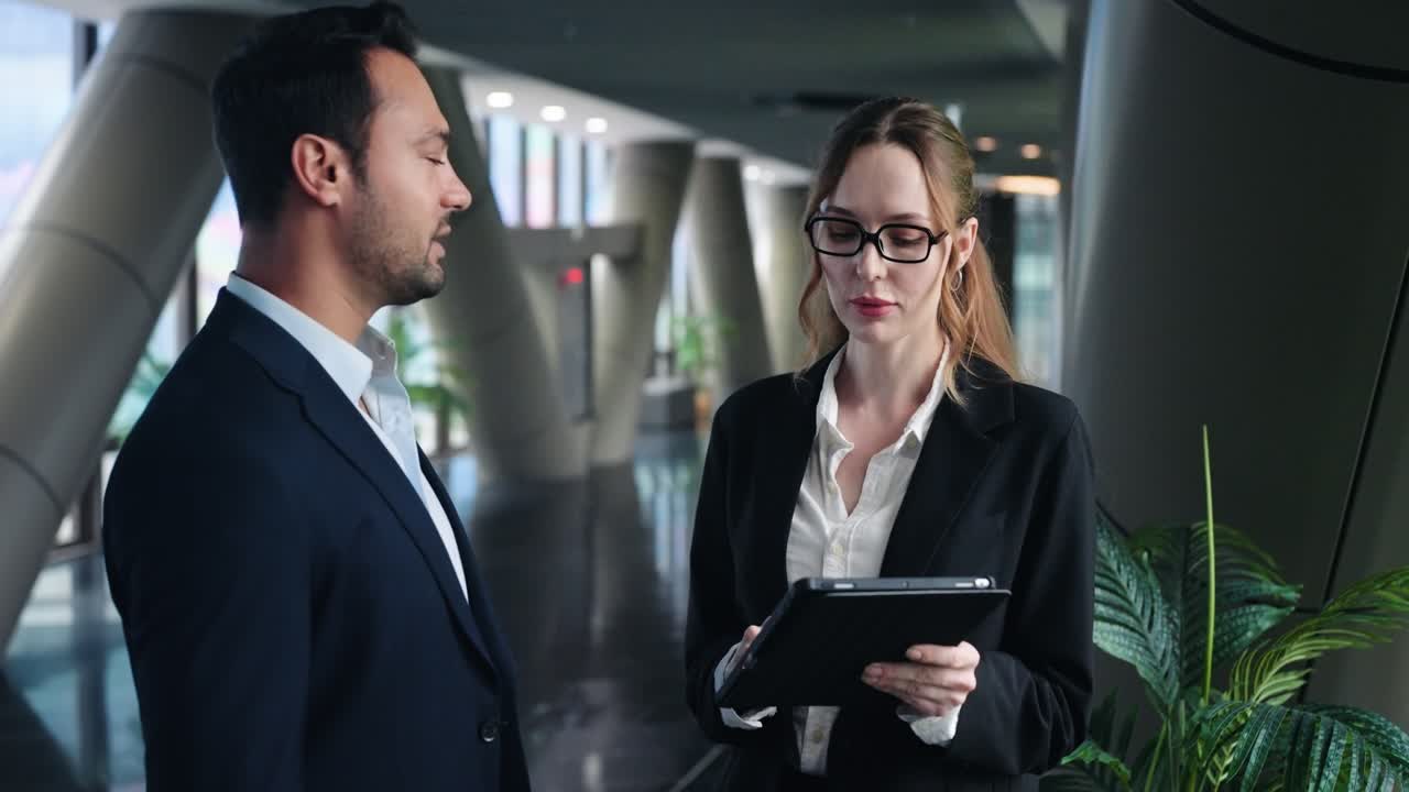 Businesspeople In Suits Converse Seriously In An Office Lobby. - medium ...