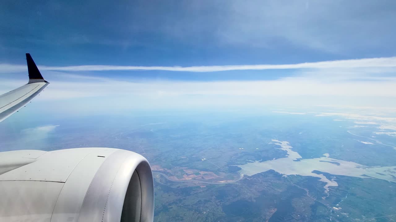 Airplane flying over lake reservoir with aircraft wing and engine seen ...