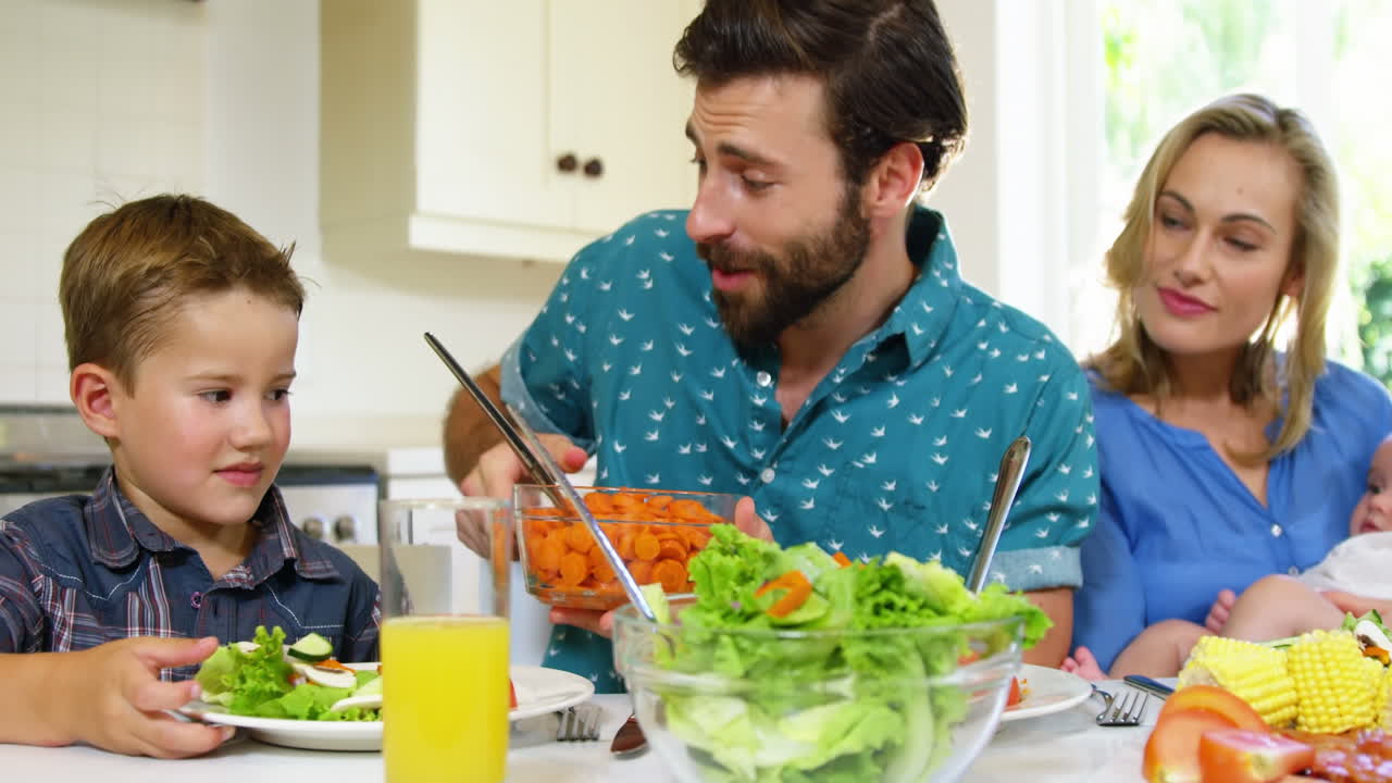 Premium stock video - Dad serving carrot to his son