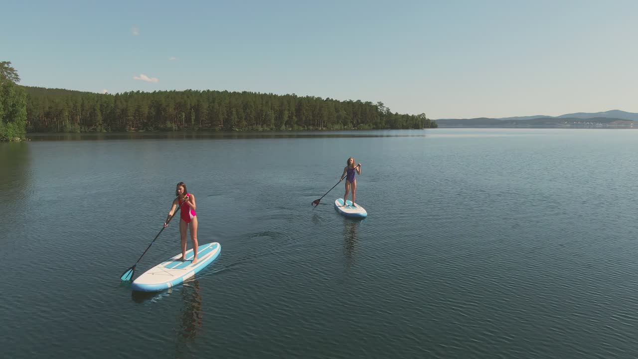 Free stock video - Aerial view of two girls in swimsuit doing paddle ...