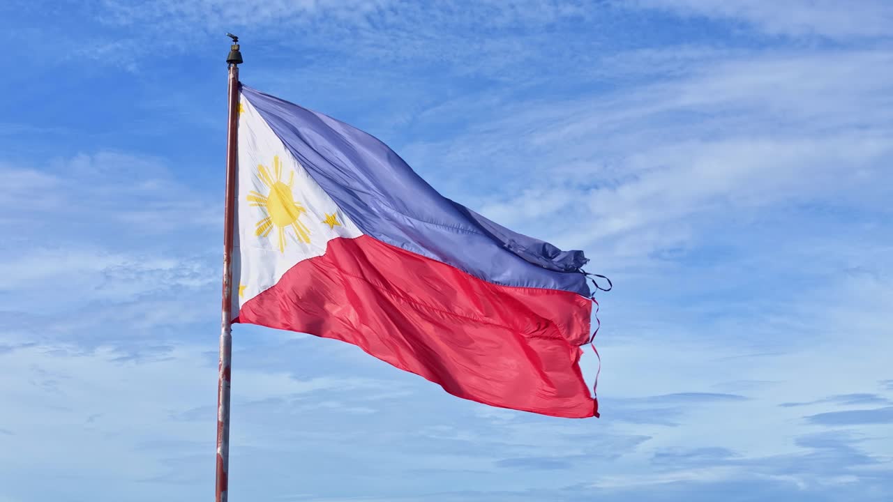 Philippine flag waving in the wind against a clear blue sky. The scene ...