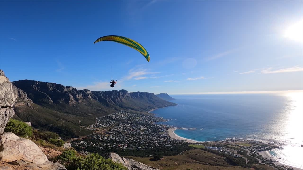 Slow motion footage of a paraglider flying towards a big wall of cliffs ...