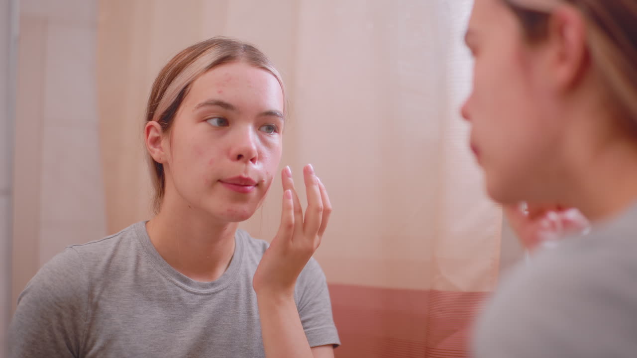 Mirror reflecting woman touching face while examining skin, focusing on ...