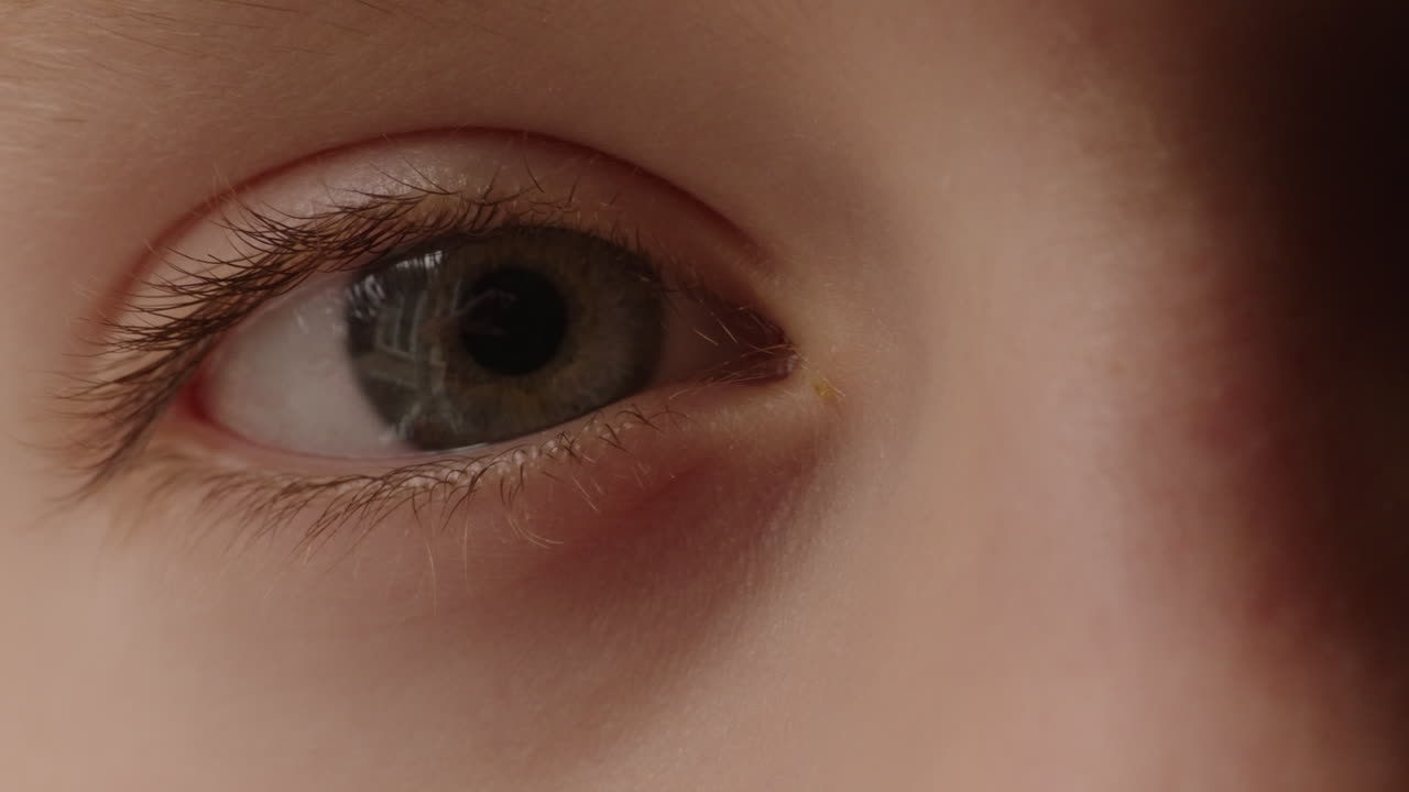 Premium stock video - Close-up view of a child's blue eye opening and ...